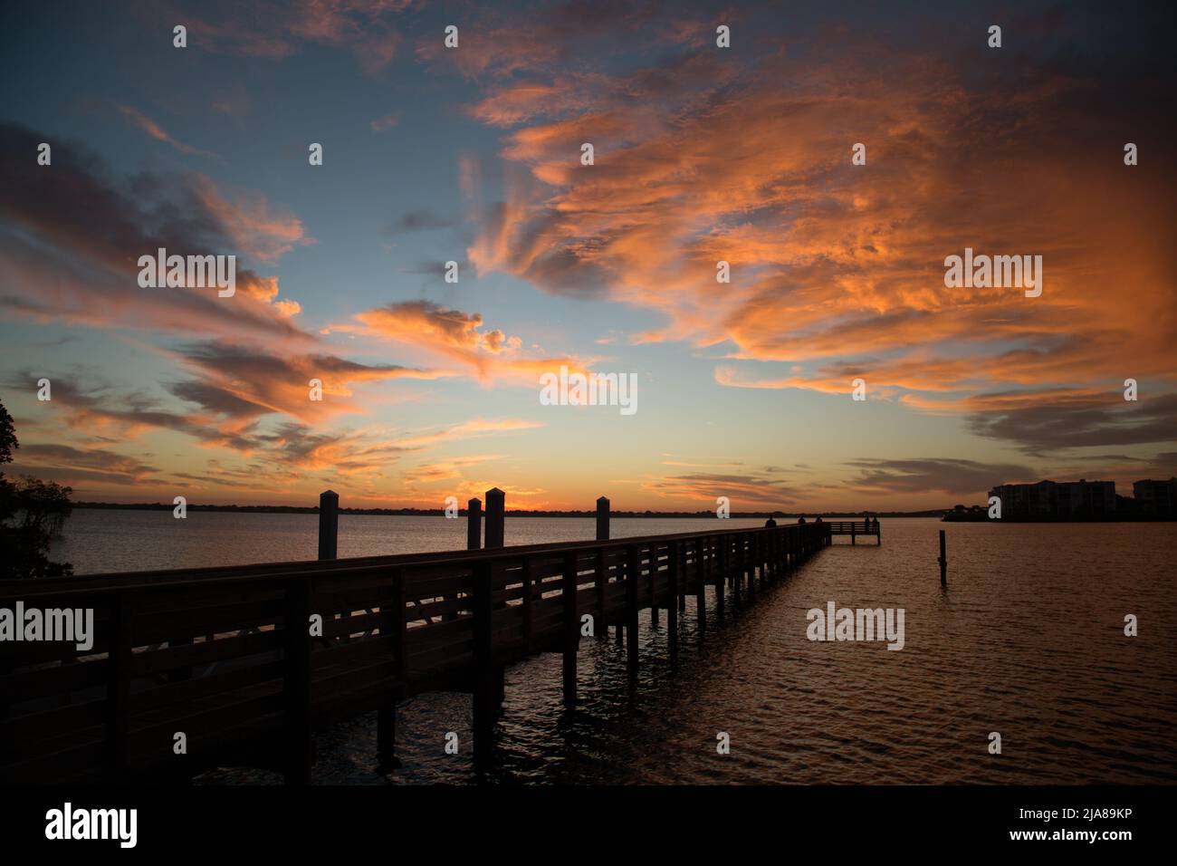 A dock stretching away from the viewer out into the ocean at early dusk ...