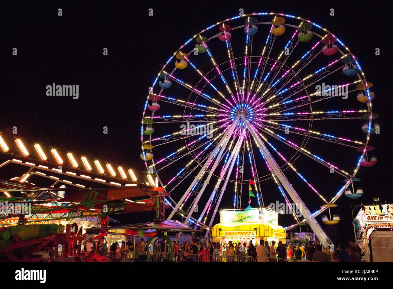 A large lit up Ferris wheel on a florida county fair ground with food ...