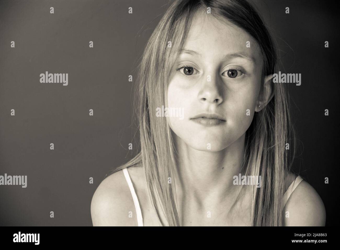 A young girl stares directly at the camera with a serious look on her ...