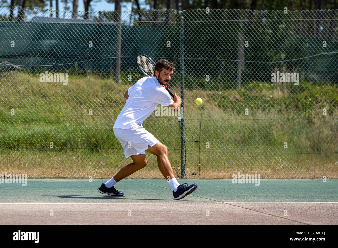 Tennis player hitting backhand at ball with racket on court Stock Photo ...