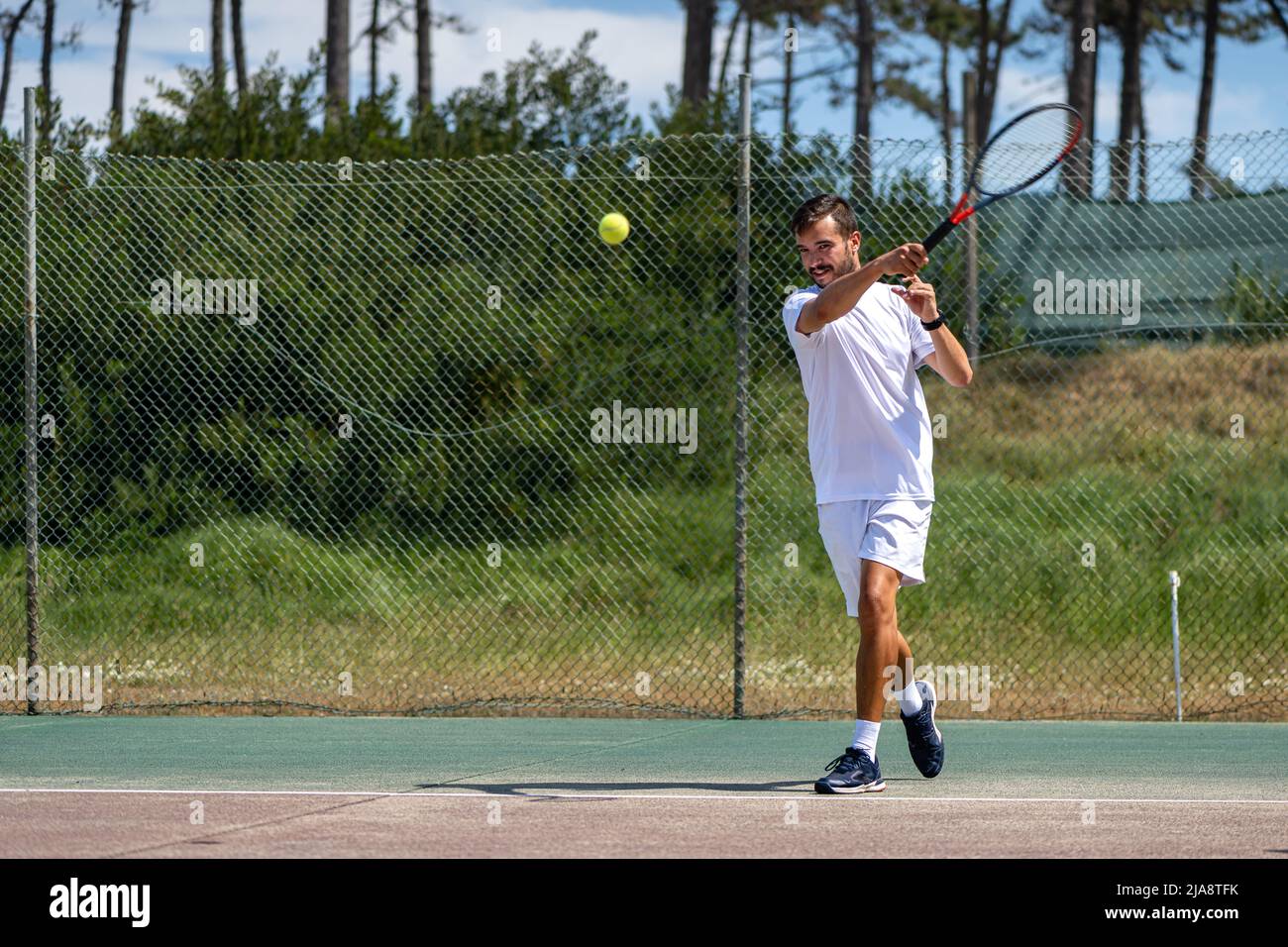 Tennis player hitting forehand at ball with racket on court Stock Photo ...