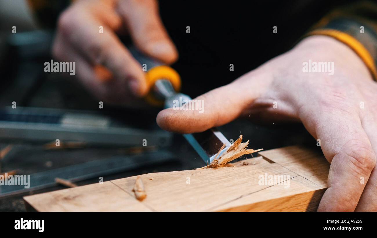 Carpentry - a woodworker cutting out the recess on the wooden block ...