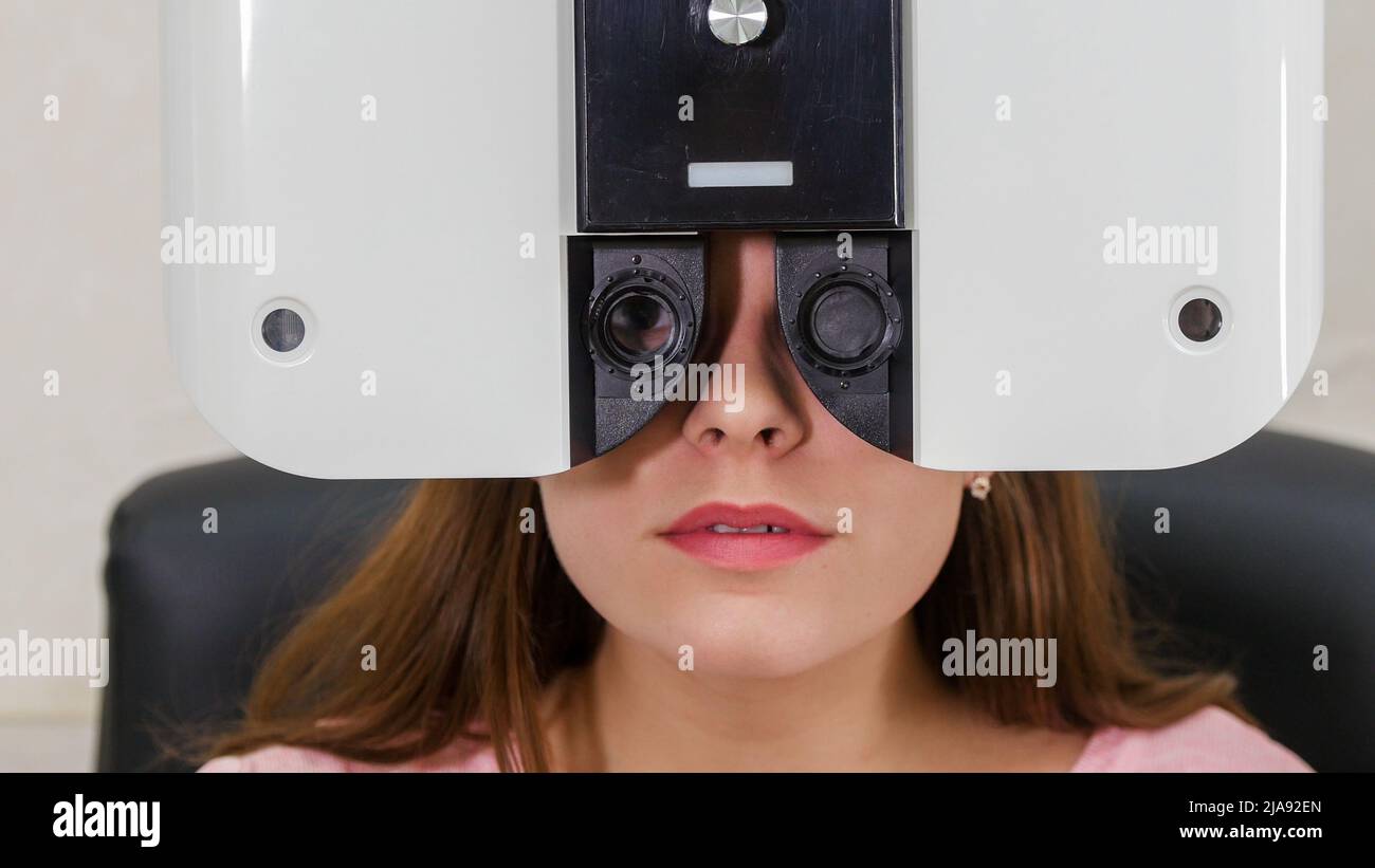 Ophthalmology treatment - a young woman with bright pink lips checking ...