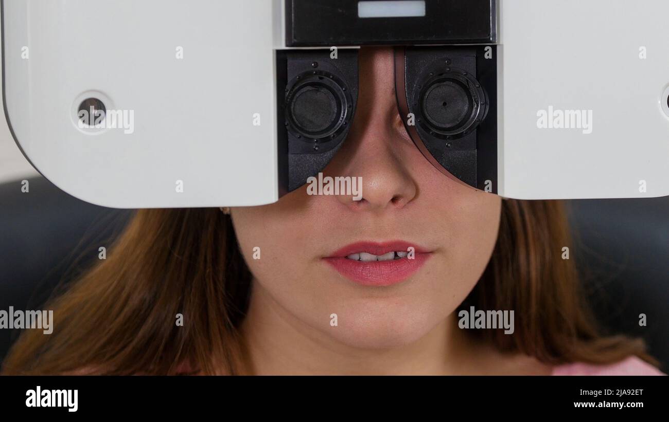 Ophthalmology treatment - a young woman checking her visual acuity with ...