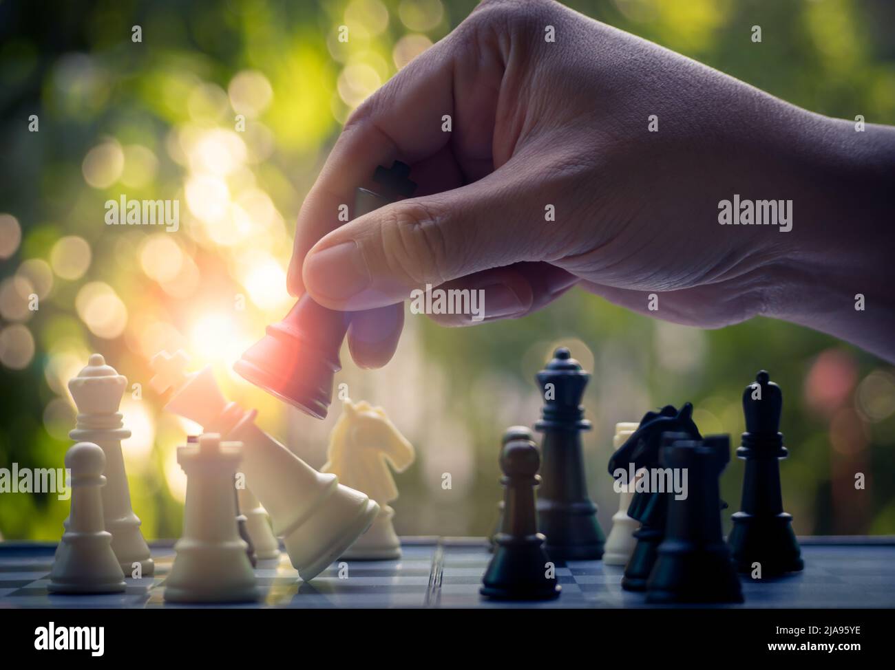 Hand holding Black king attack white king of chess battle on board ...