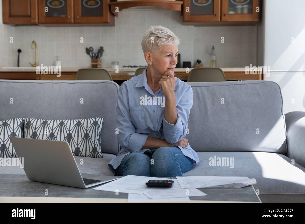 Confused old lady sit on sofa think about paying debts Stock Photo - Alamy