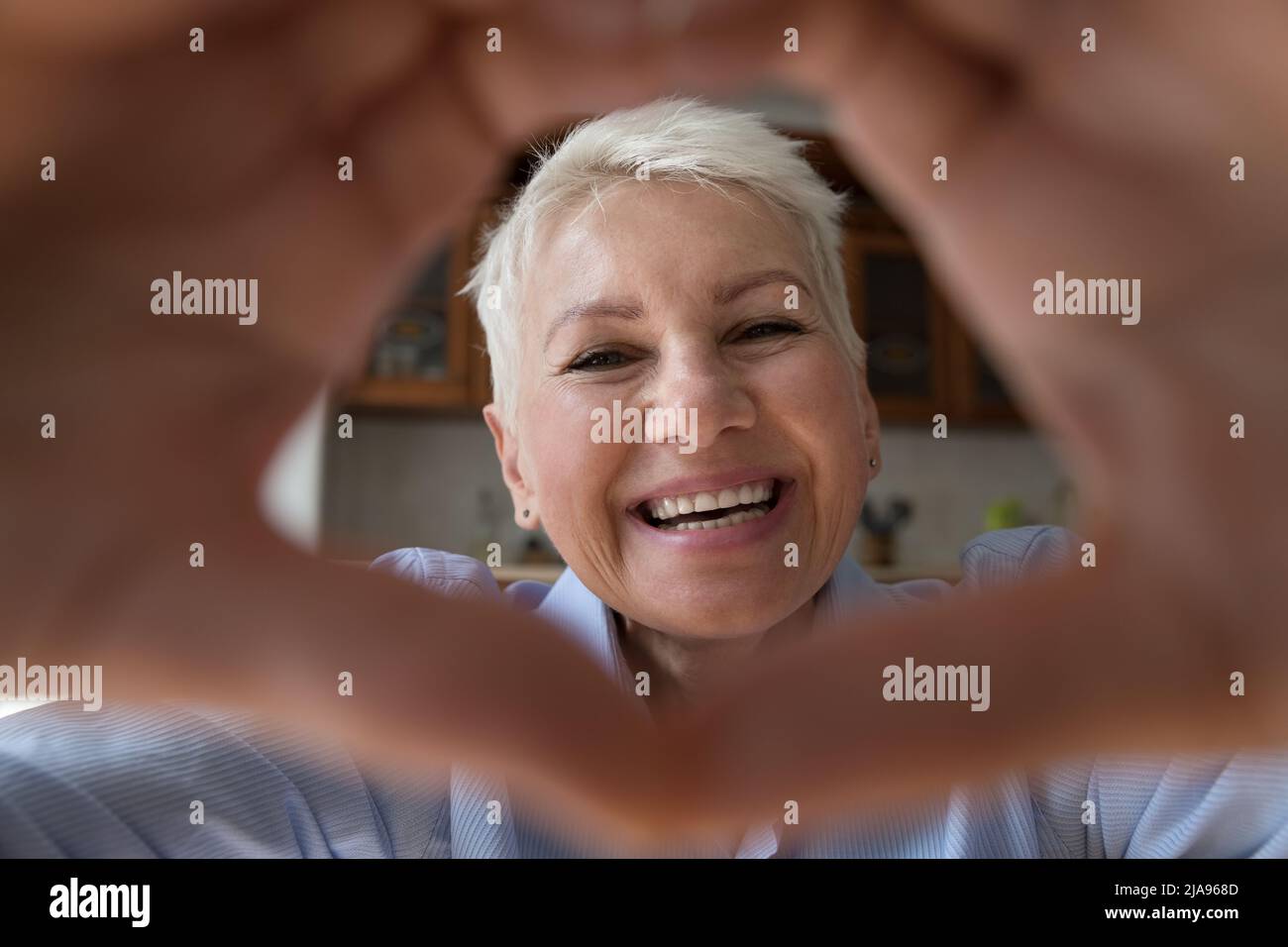 Happy smiling old lady look at camera in finger heart Stock Photo - Alamy