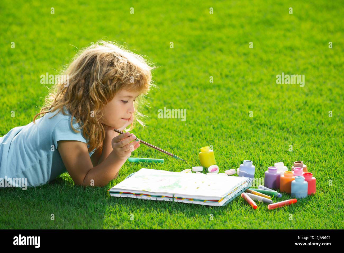 Child painting drawing art. Child boy draws in park laying in grass ...