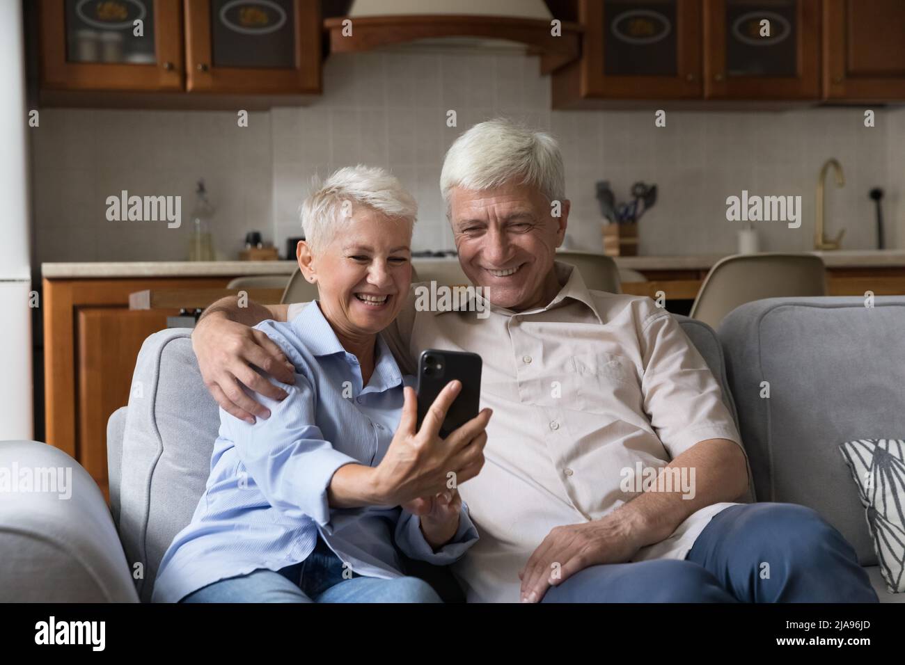 Loving aged couple hug on sofa shoot selfie on cellphone Stock Photo ...
