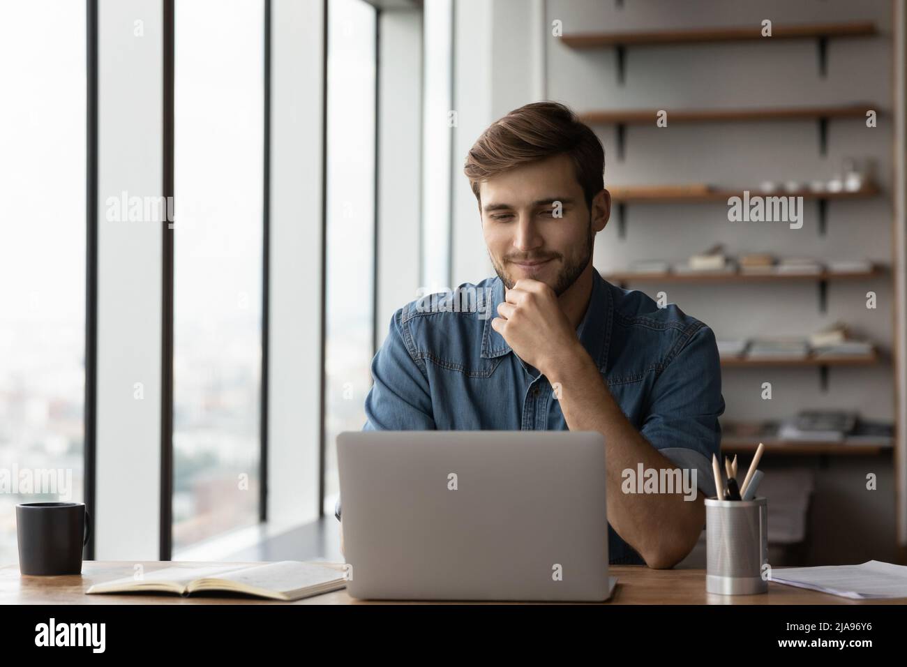 Happy satisfied millennial man using laptop at office workplace Stock ...