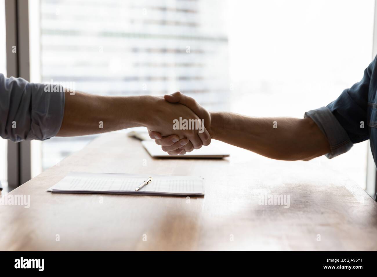 Two businessmen shaking hands over conference table in office Stock ...