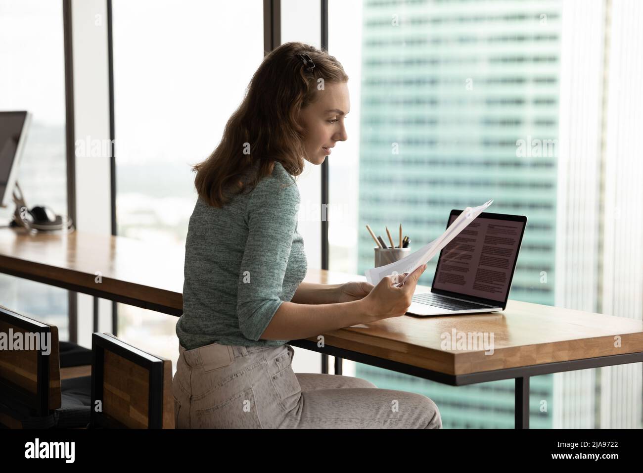 Serious student girl working on research paper, reviewing paper letter ...