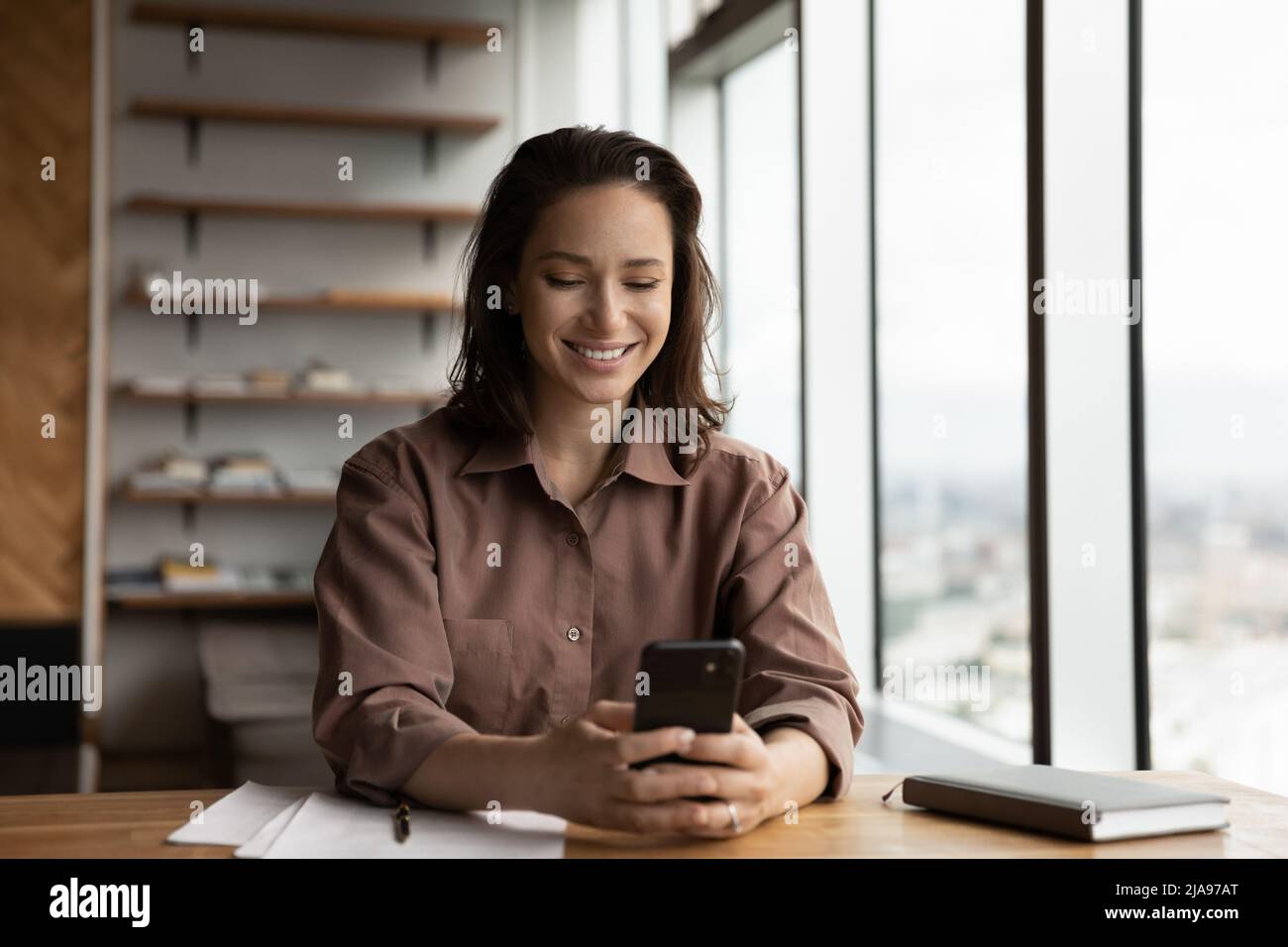 Happy female employee reading text message on cell screen Stock Photo ...