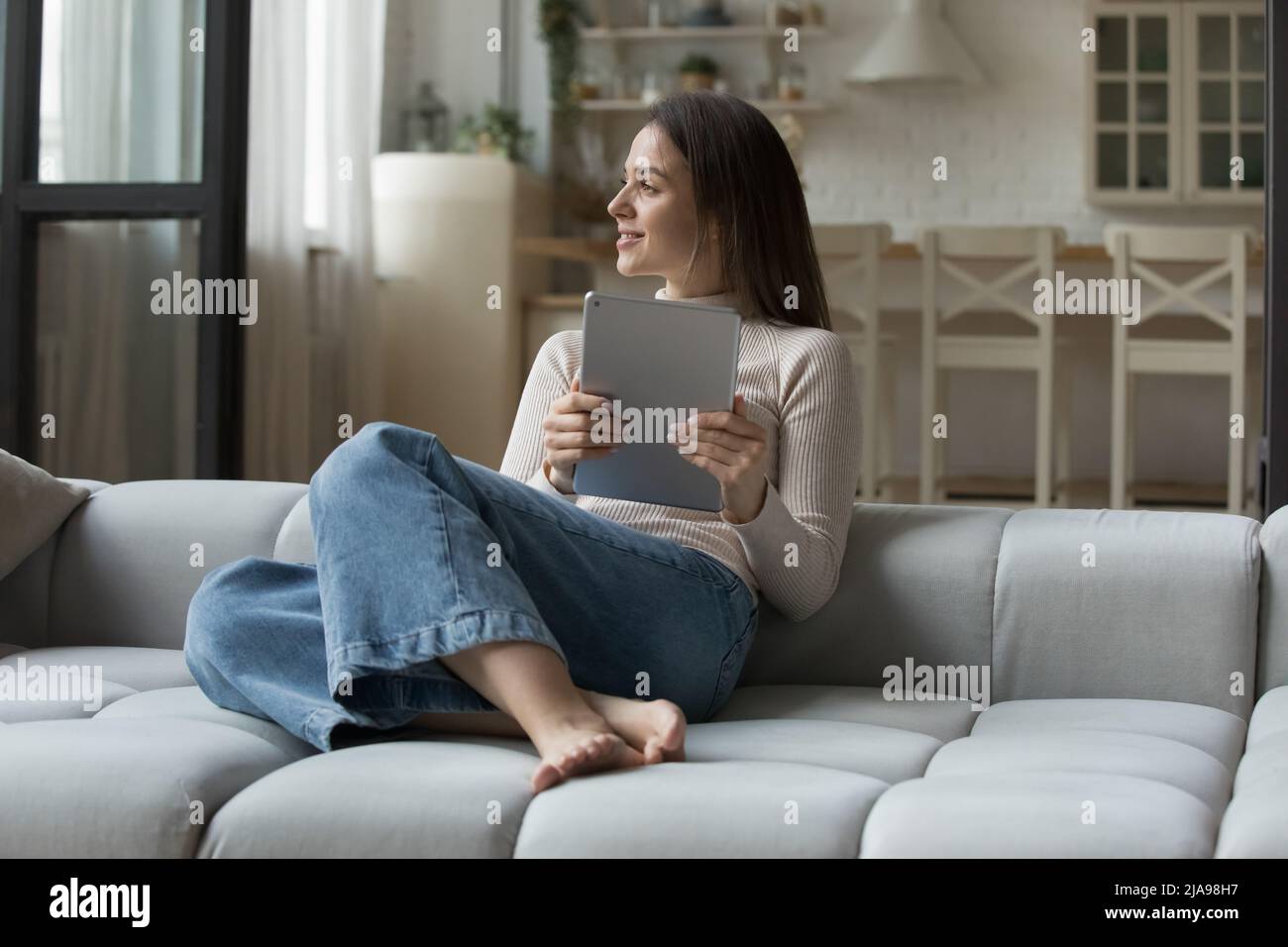 Happy dreamy gadget user girl holding digital pad Stock Photo - Alamy