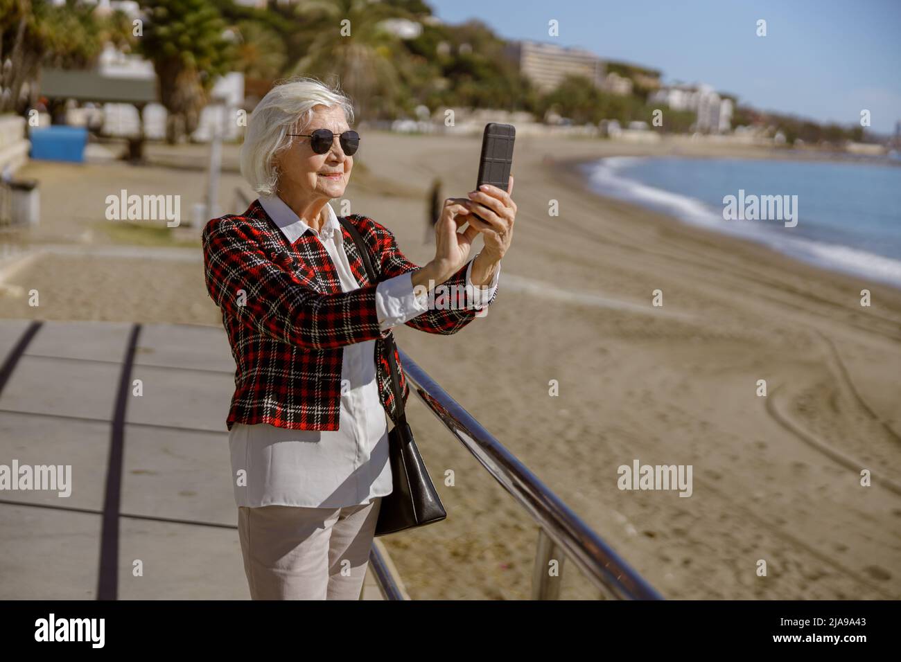 Urban elderly woman relaxing outdoors by sea Stock Photo - Alamy