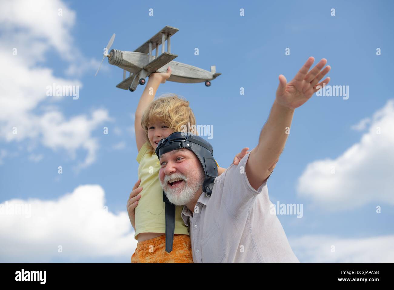 Young grandson and old funny excited grandfather having fun with toy ...