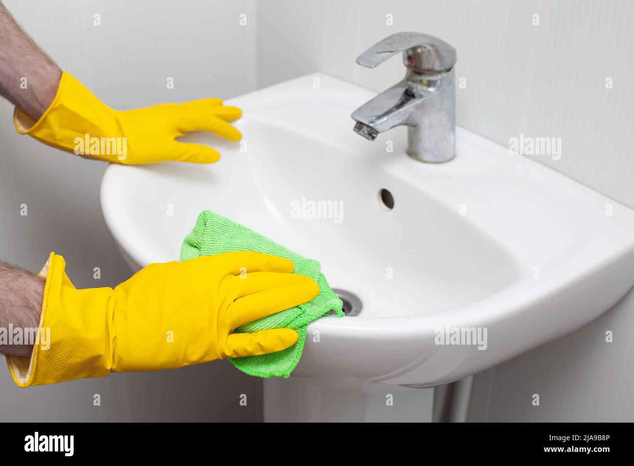 Rubber gloved hand cleaning sink with duster Stock Photo - Alamy