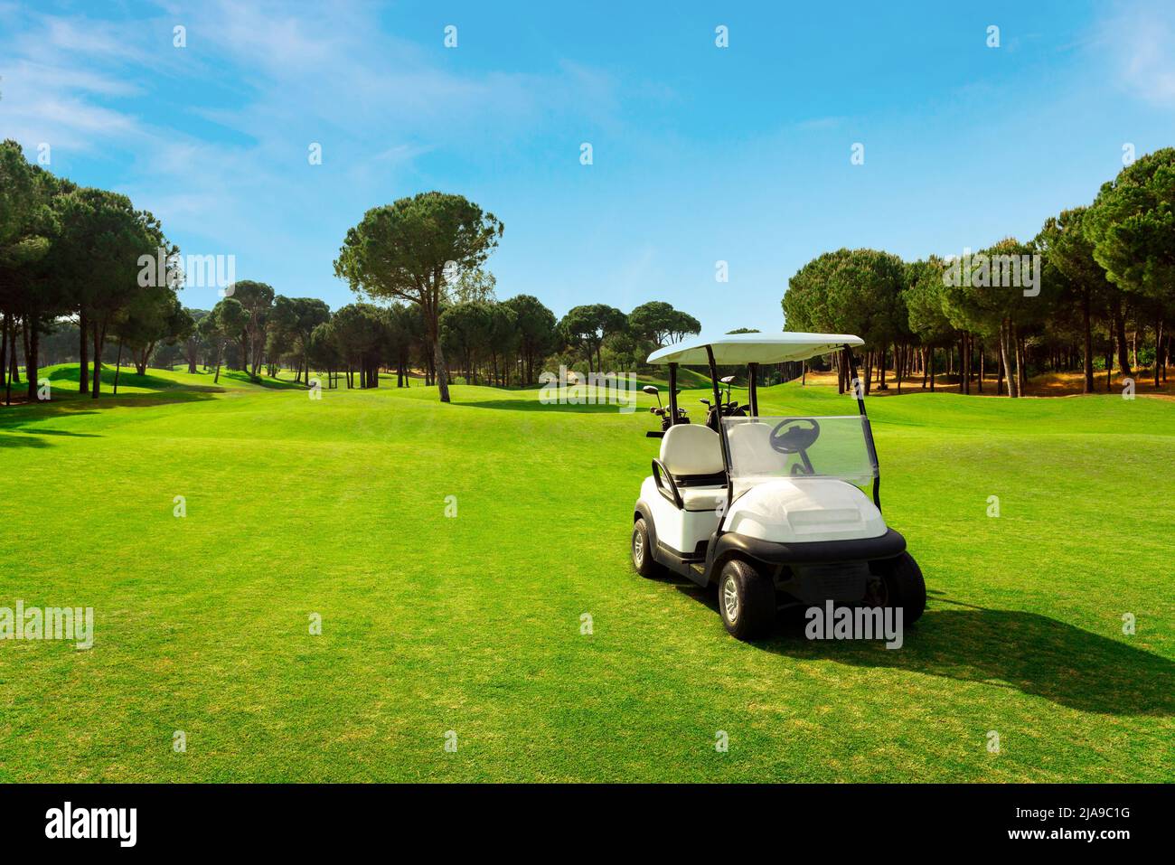 Golf cart on a golf course with green grass field with blue sky and ...