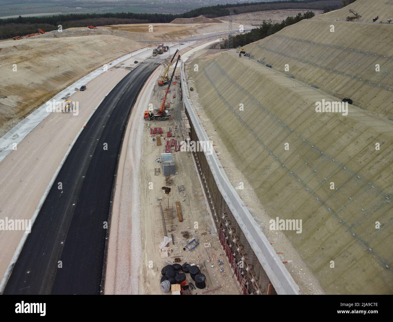 Workers reinforce the slope over the new road. Road construction in ...