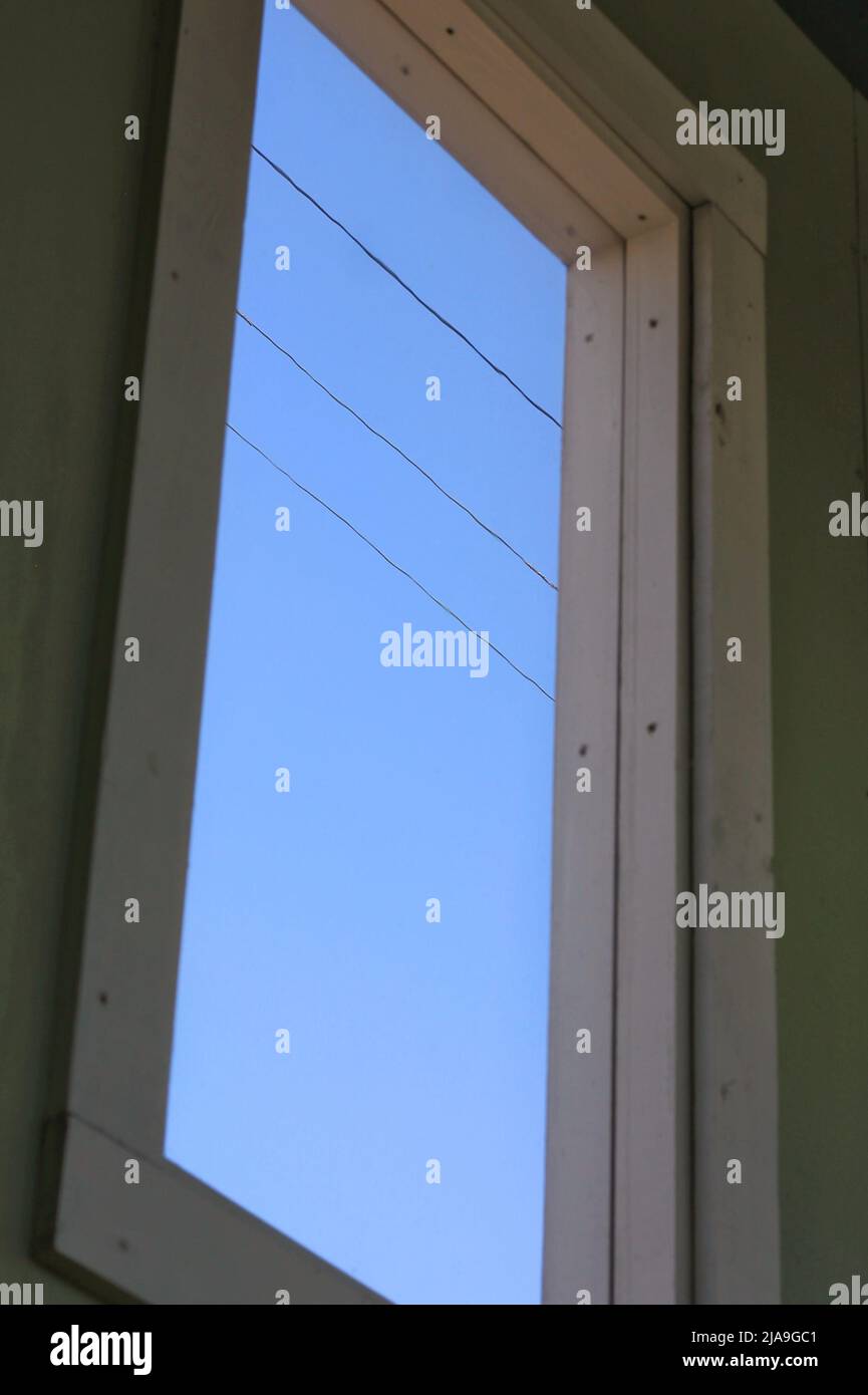 Looking up thru an industrial window to see power lines crossing the ...