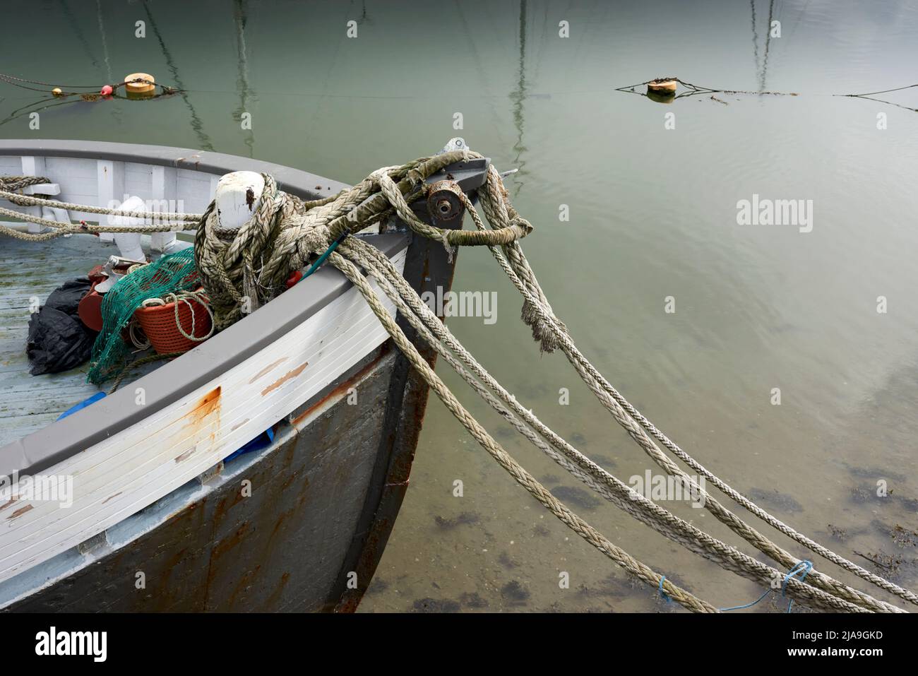 Bow of wooden fishing boat with rope mooring lines, at low tide in ...