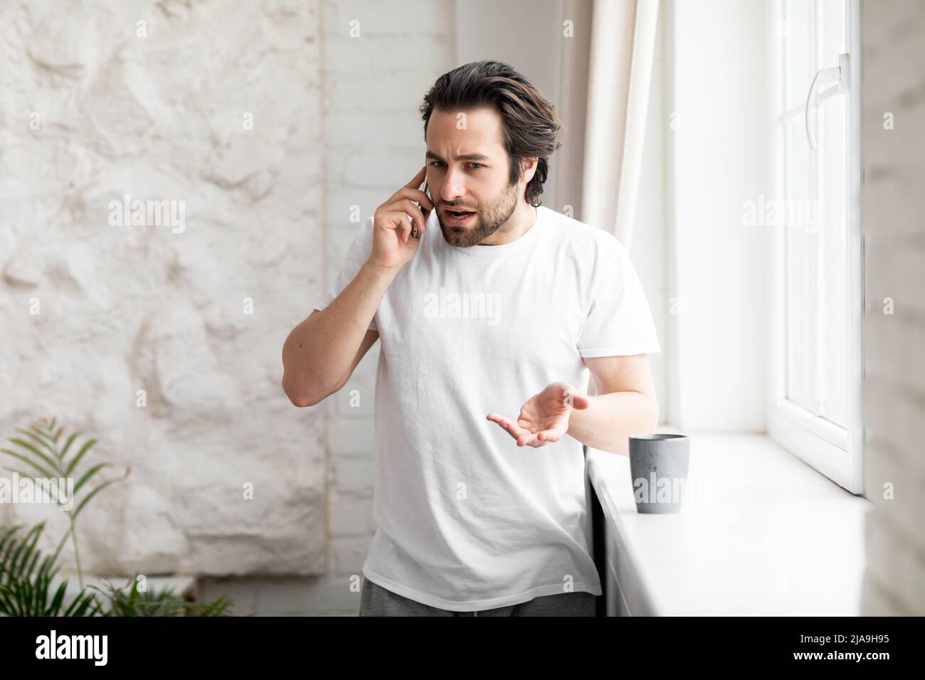 Angry man having phone call while drinking coffee Stock Photo - Alamy