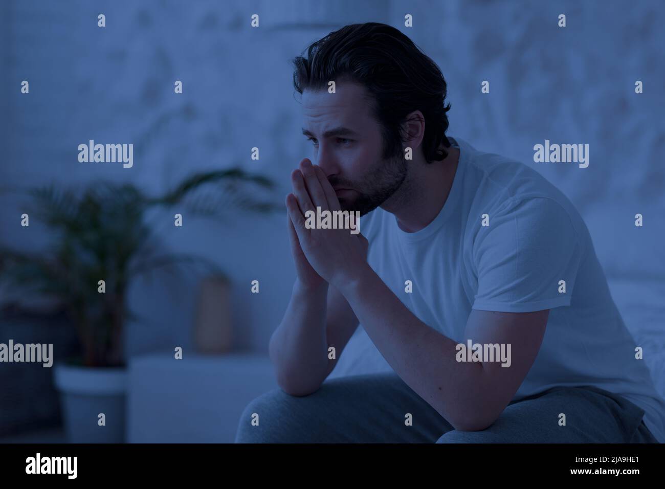 Sleepless guy sitting on bed at night, thinking about something Stock ...