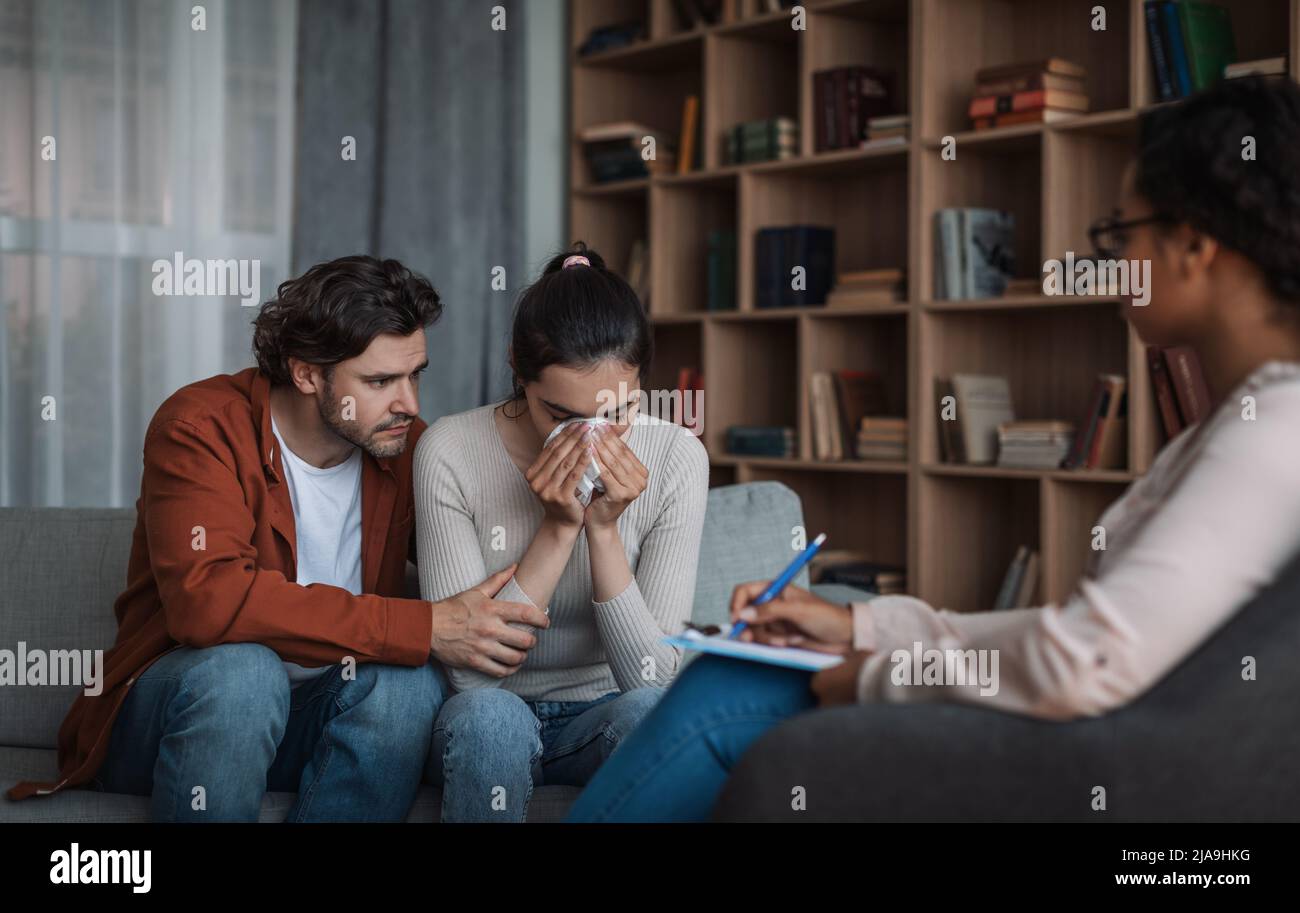 Despaired young european man calm crying african american lady on ...