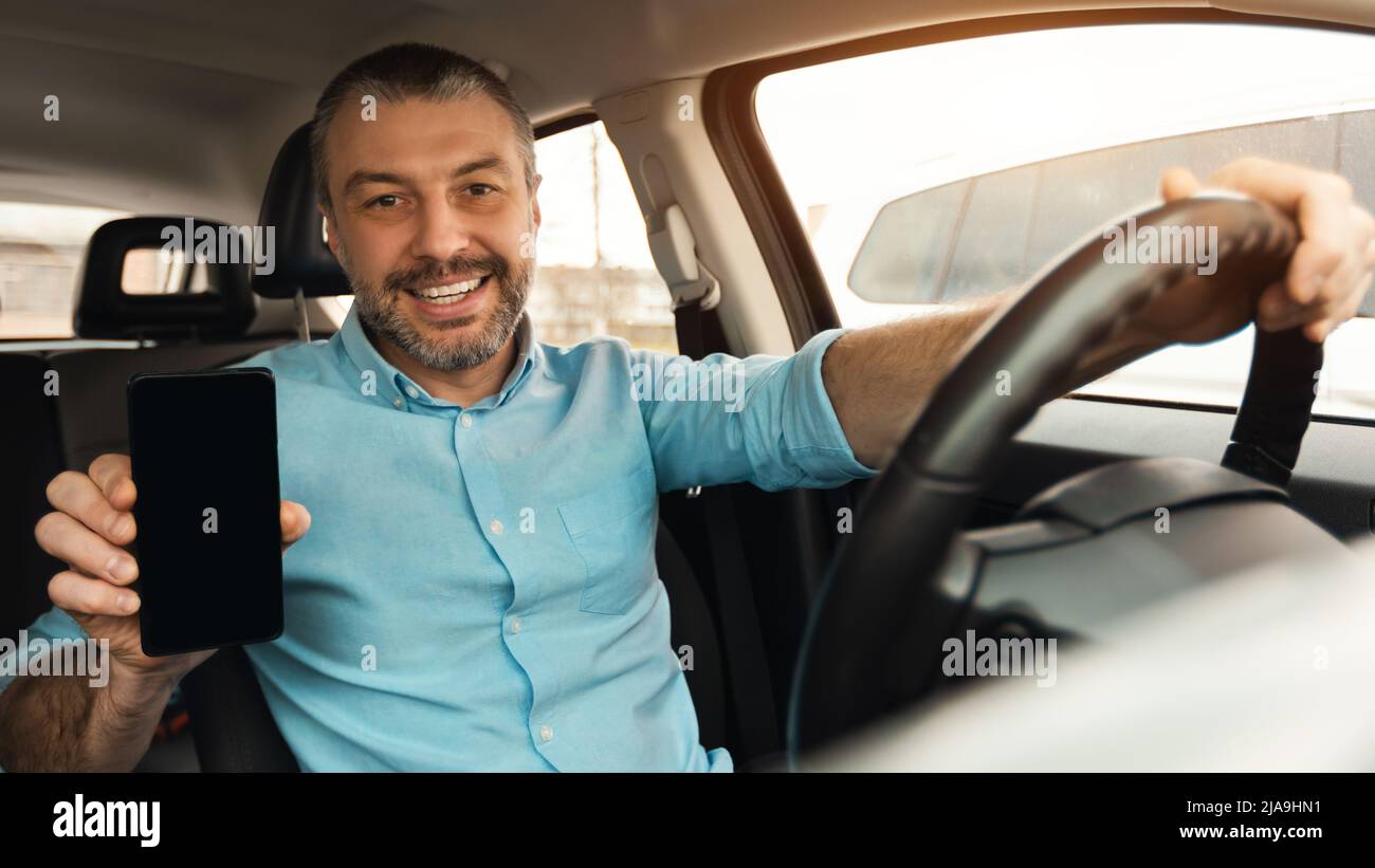 Happy driver using showing smartphone with empty screen Stock Photo - Alamy