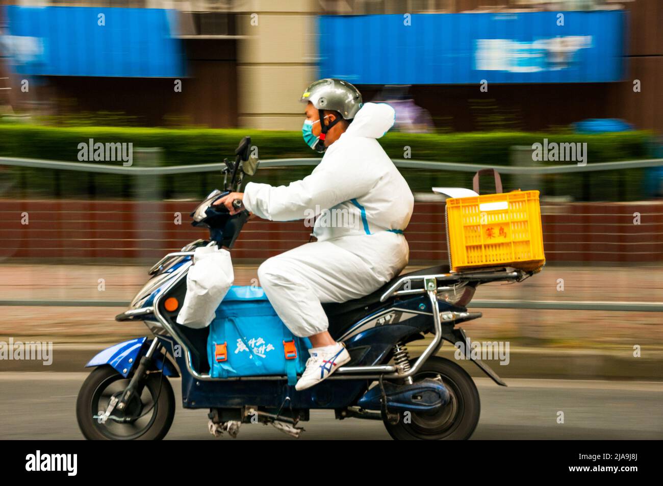 A delivery rider wearing white PPE gear speeds past on a scooter in ...