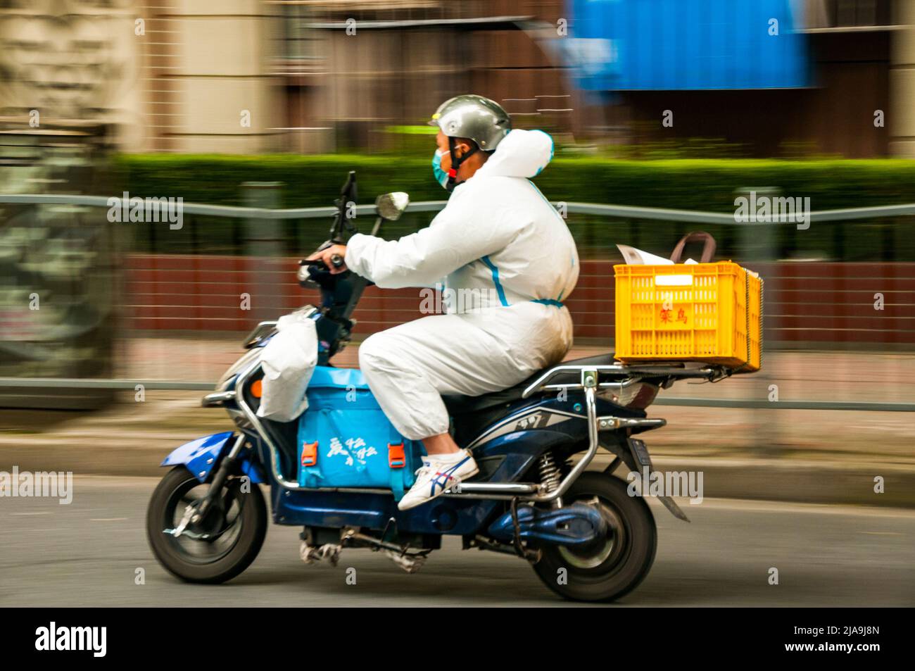 A delivery rider wearing white PPE gear speeds past on a scooter in ...