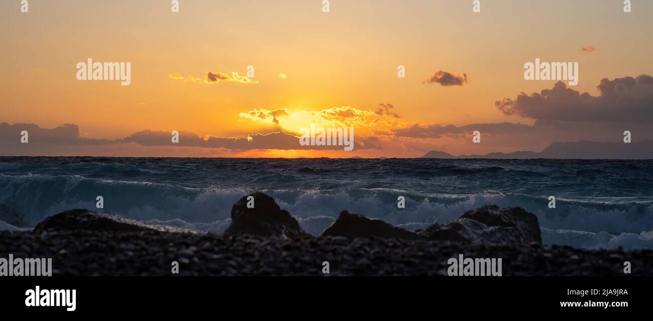 Sea wave at sunset in gold hour hitting a rock on the beach Stock Photo ...