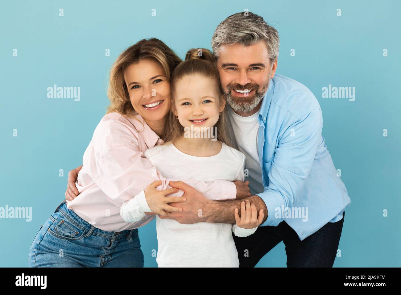 Happy Parents Hugging Little Daughter Posing Over Blue Studio Background Stock Photo - Alamy