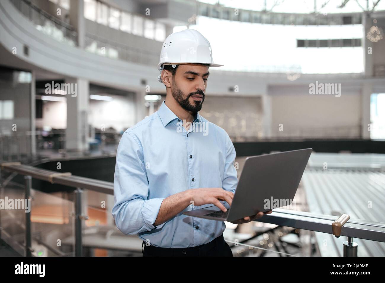 Pensive busy millennial arab guy engineer in safety helmet with beard ...