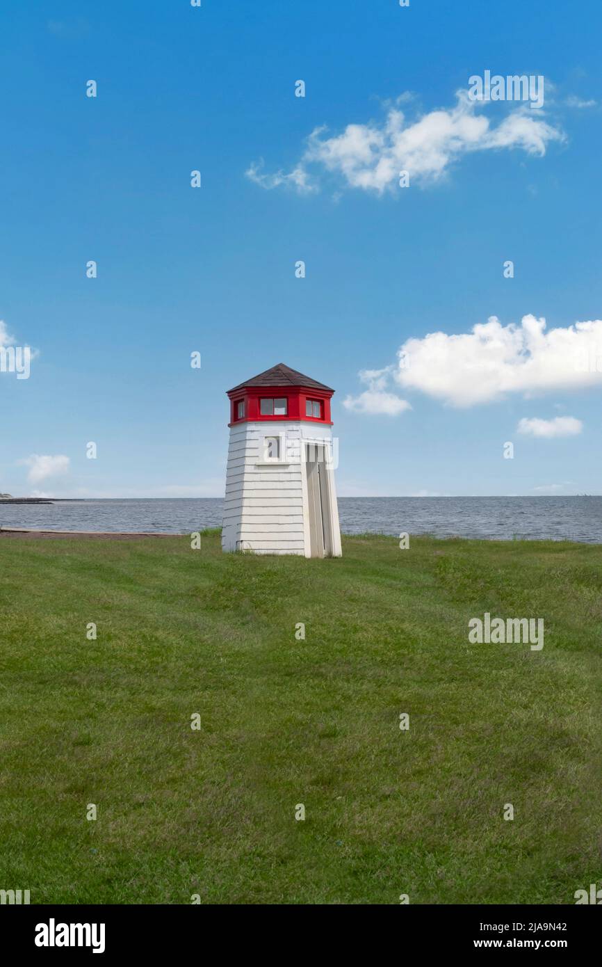 Small white and red roof lighthouse by the ocean on green grass with ...