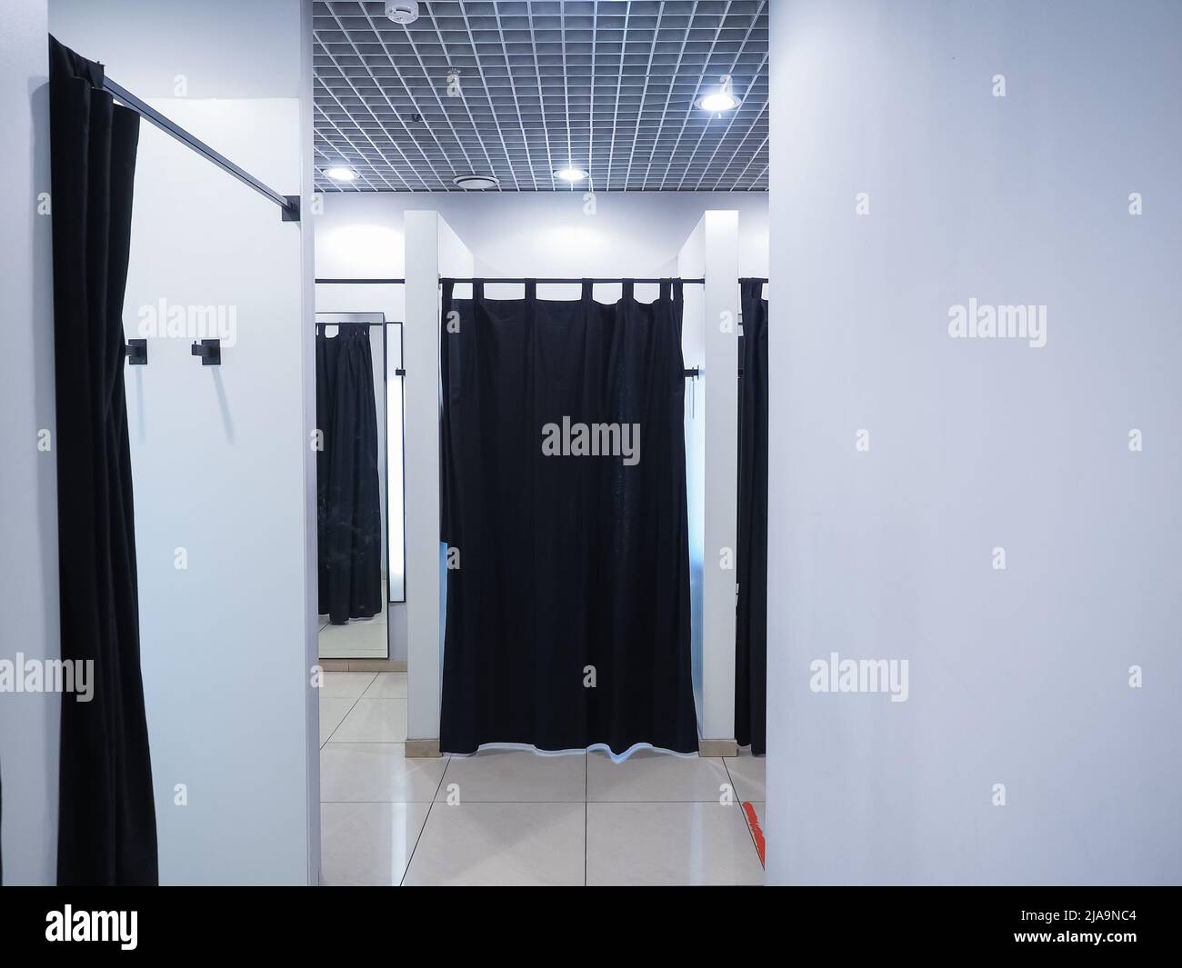Bright dressing room with white walls and black curtains on booths ...
