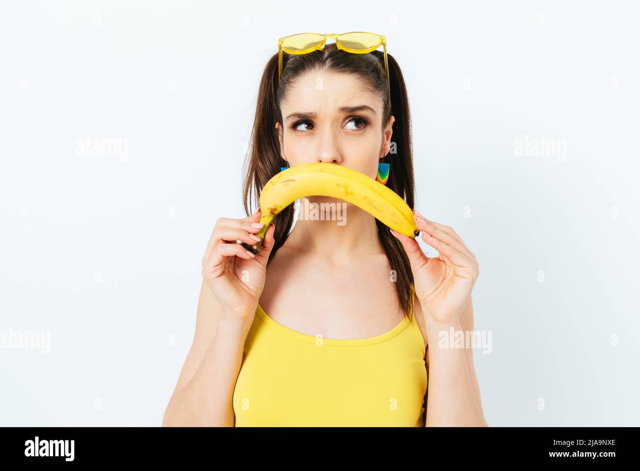 Portrait of young woman wearing yellow top and sunglasses holding ...
