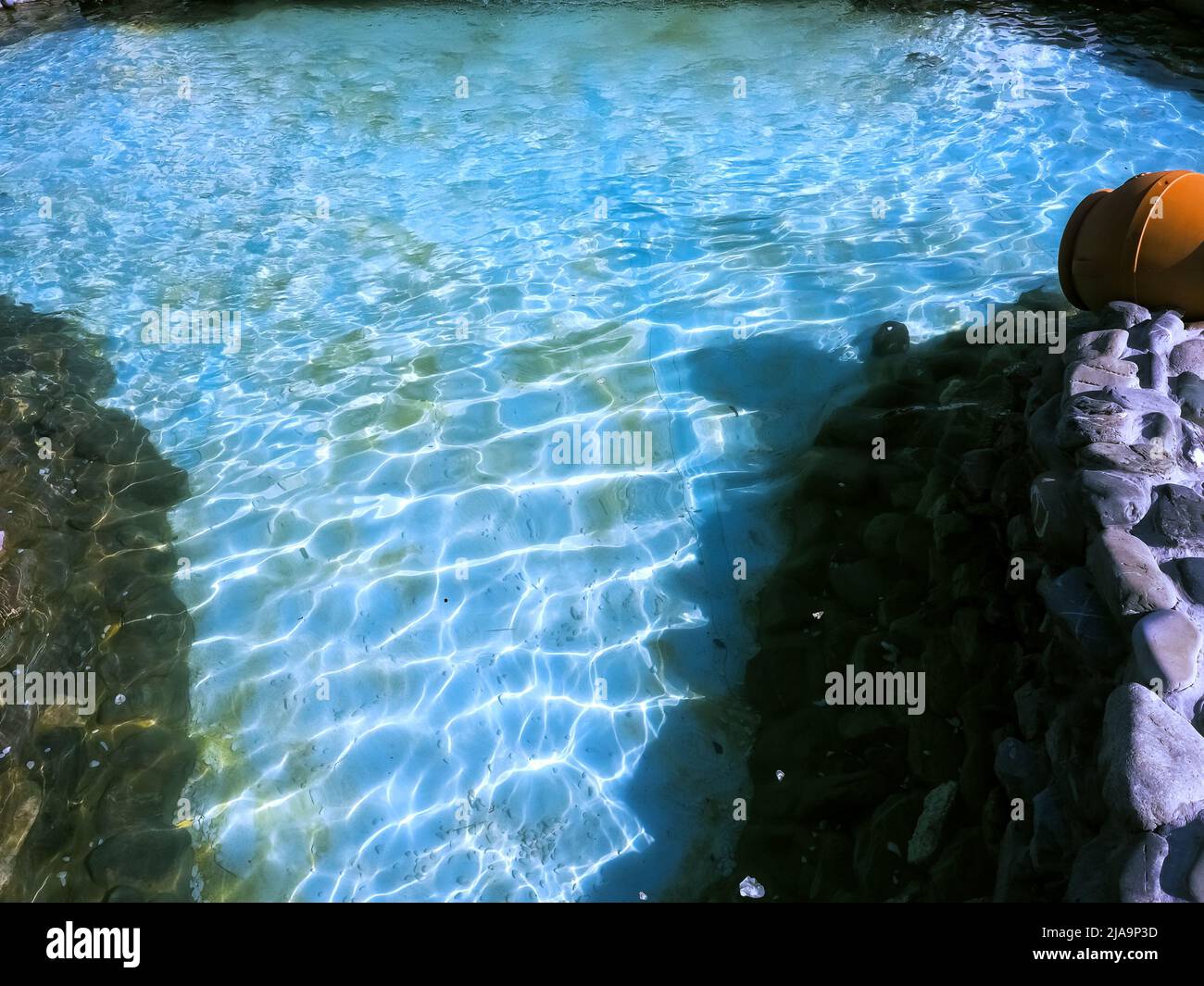 Blue summer decorative pool with transparent water shining in sun and ...