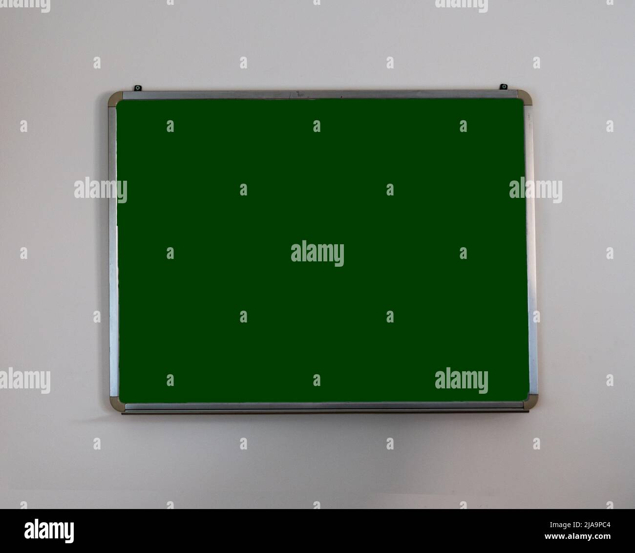 large green chalkboard hanging on a white wall, with copy-space to ...