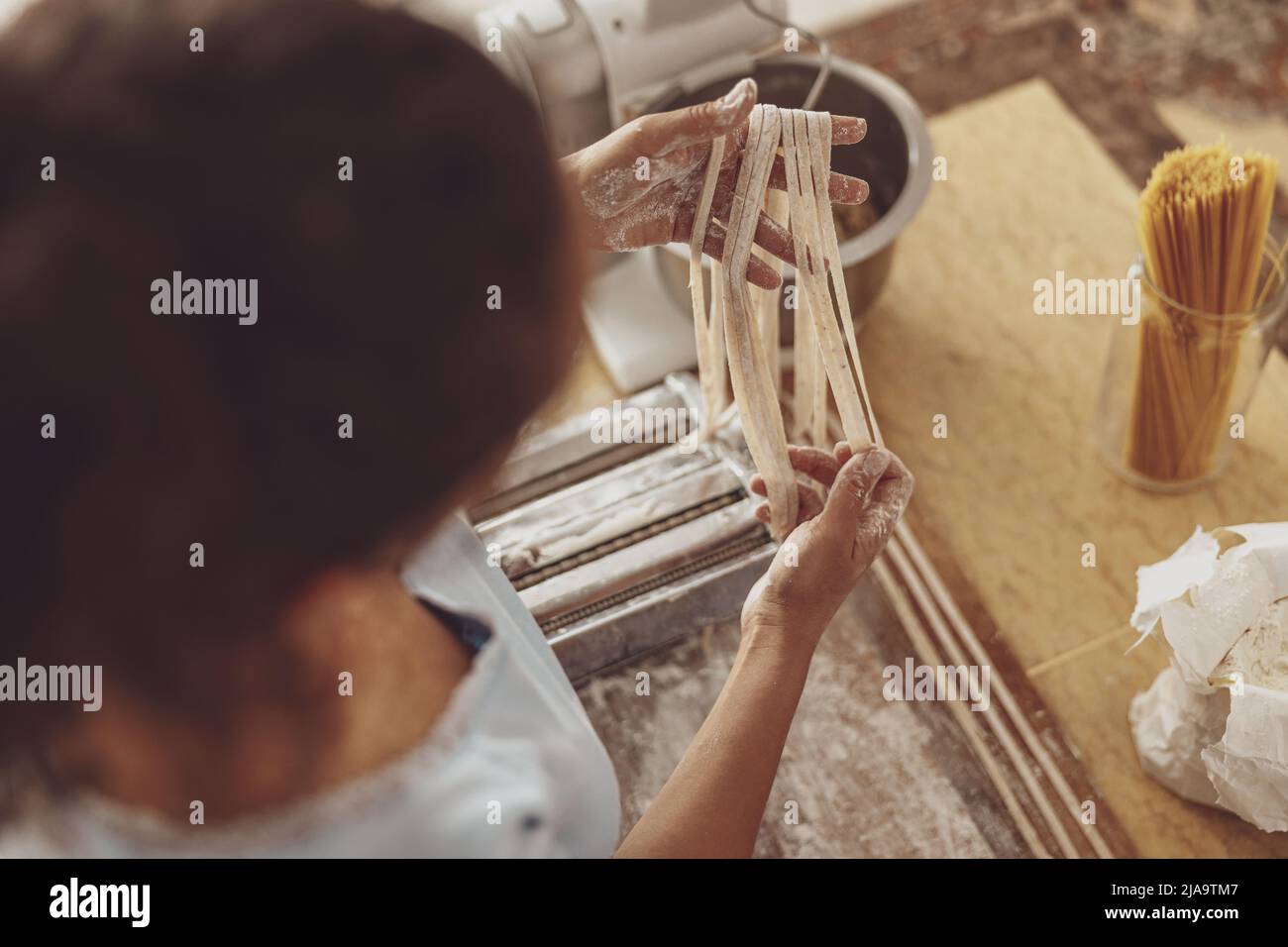 Homemade noodles in the hands of a woman standing in the kitchen. A ...