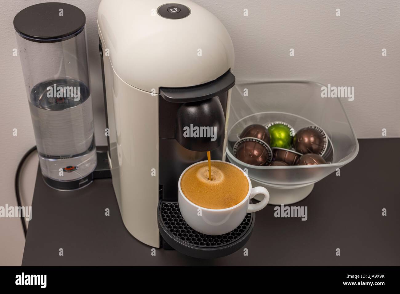 View of pouring aromatic coffee into white cup from capsule coffee ...