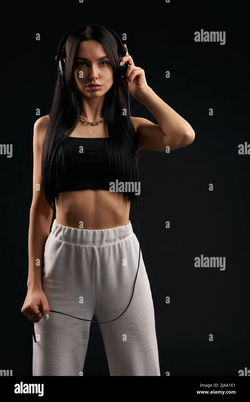 Gorgeous dark haired wonan in sporty outfit posing with earphones on ...