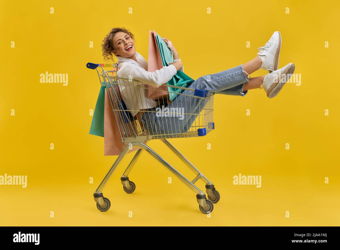 Delighted woman hugging bright paper bags, while sitting in shopping ...