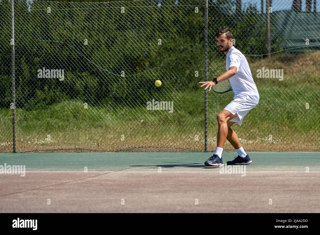 Tennis player hitting forehand at ball with racket on court Stock Photo ...