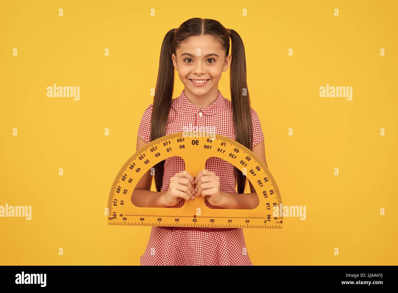 happy child hold school math tool protractor ruler on yellow background ...