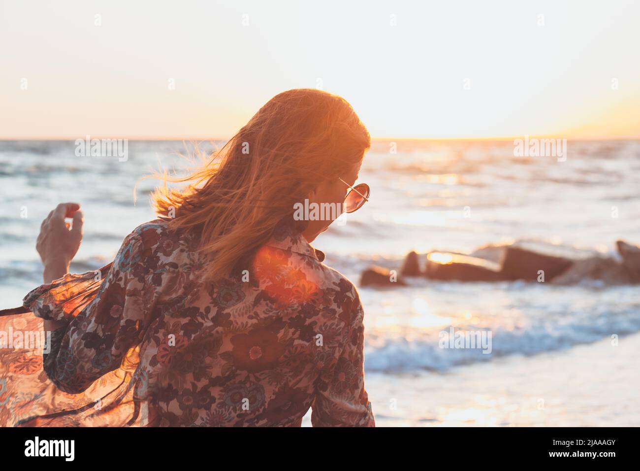 Woman enjoying sunset at the beach Stock Photo - Alamy