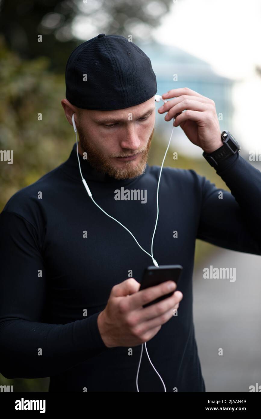 Close-up shot of young white man with beard putting headphone in his ...