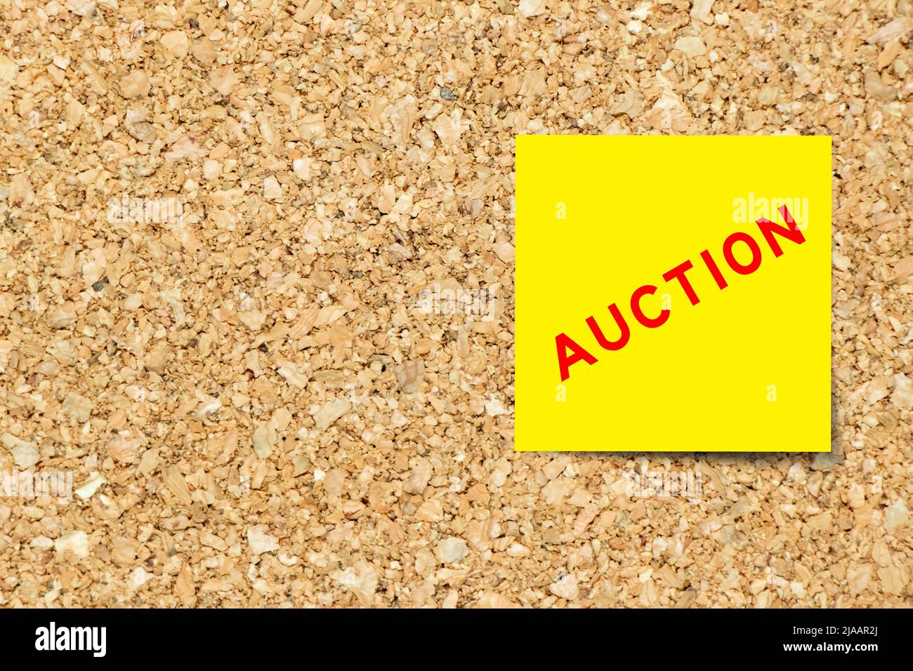 Yellow note paper with word auction on cork board background with copy ...