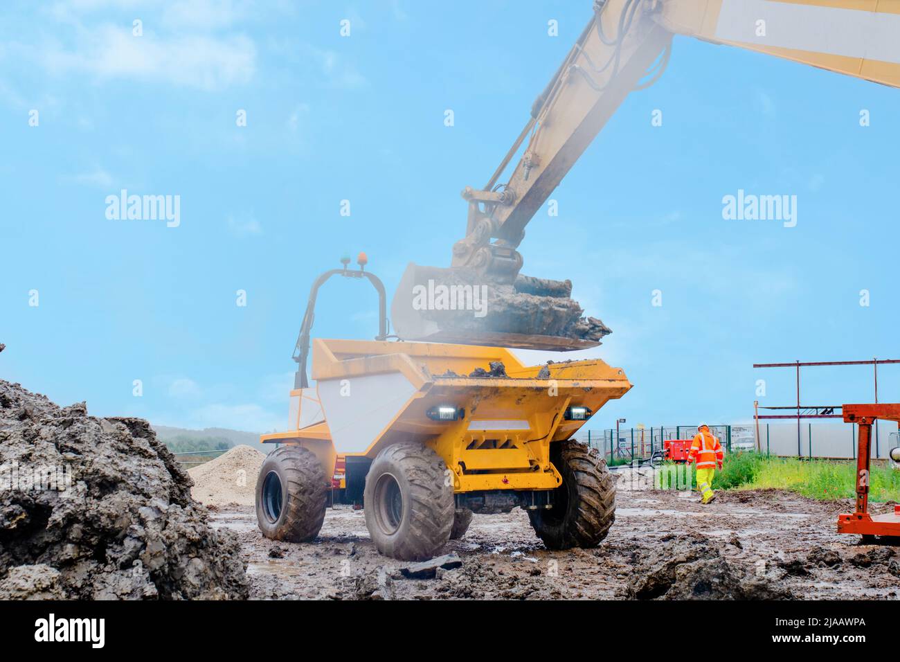 Excavator under rain loading dumper truck with as dug materials during ...