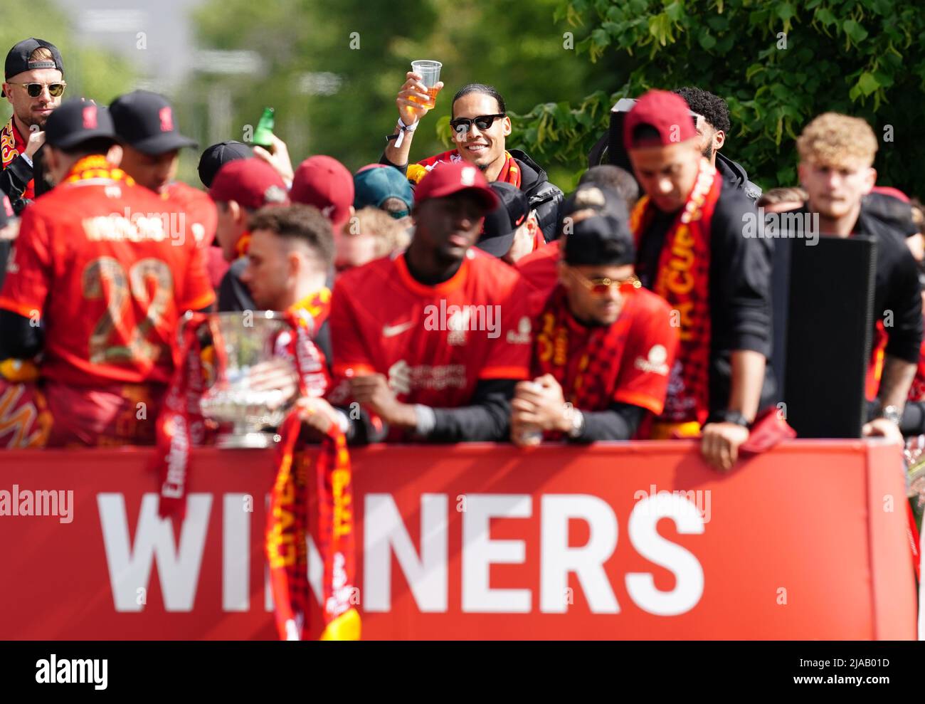 Liverpool's Virgil van Dijk (background) raises a cup in a open-top bus ...